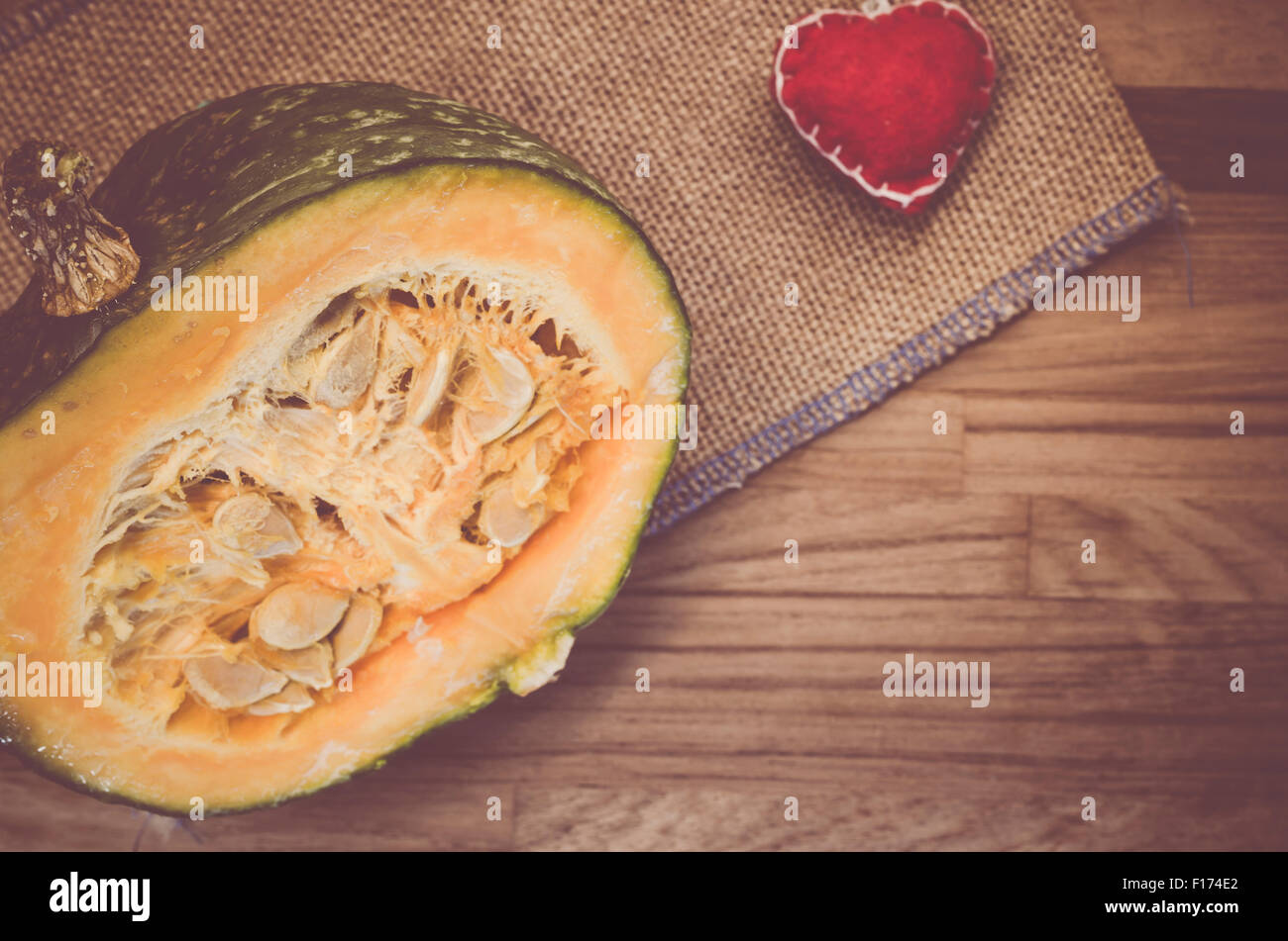 fresh and ripe half cut pumpkin on a natural wood and jute background ...
