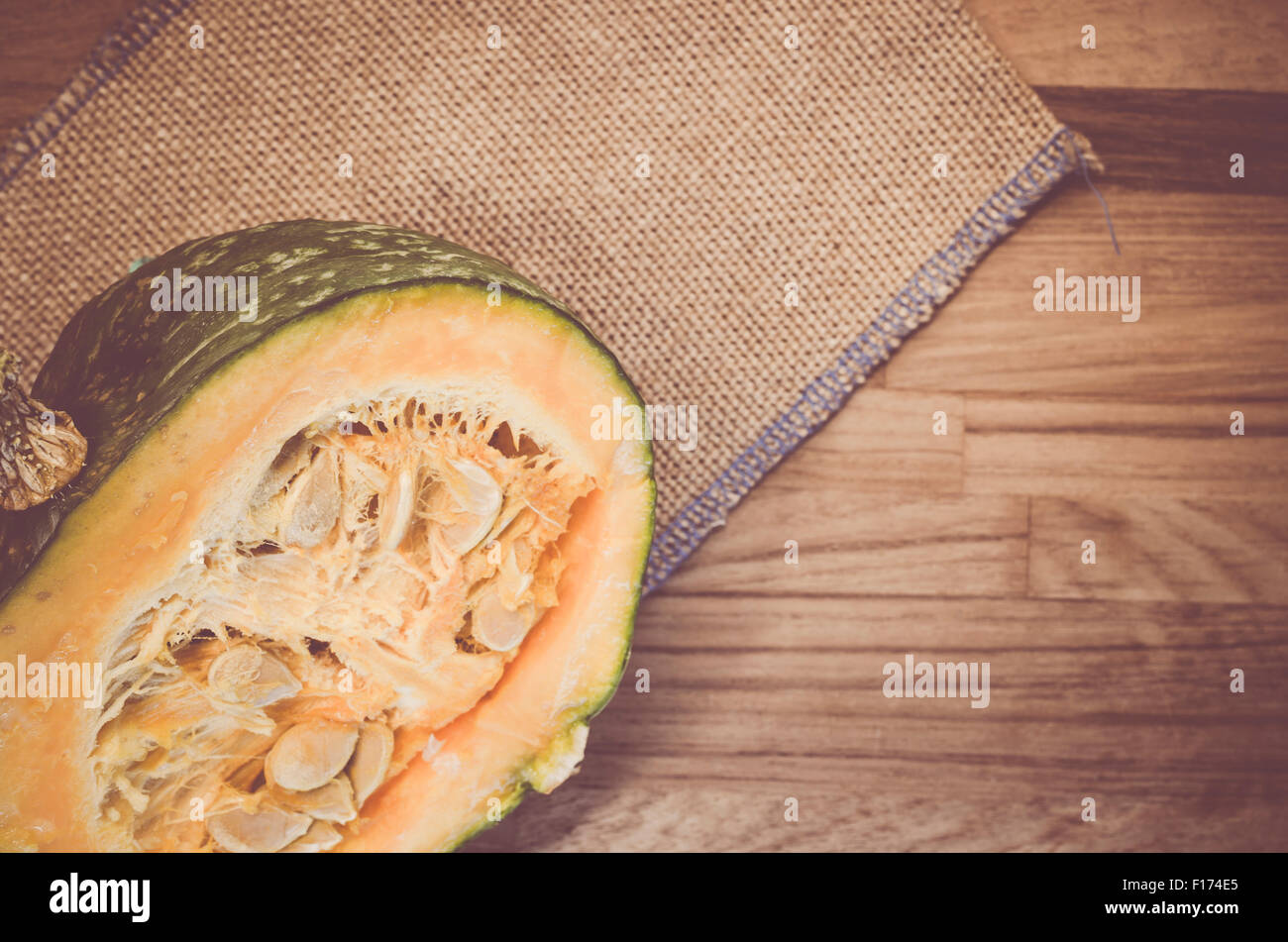 fresh and ripe half cut pumpkin on a natural wood and jute background ...