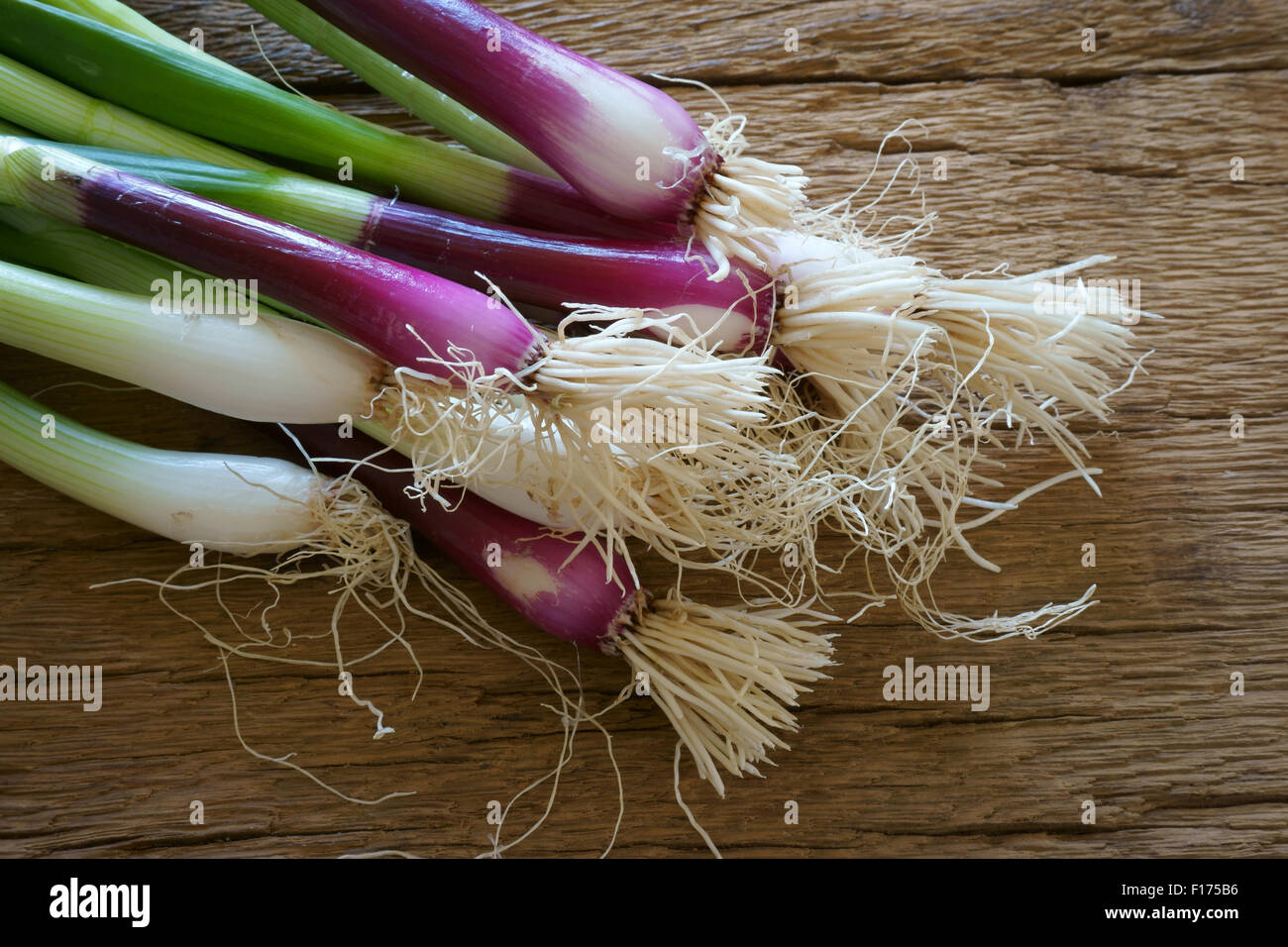 Bunch of fresh red spring onions on rustic wooden cutting board Stock ...