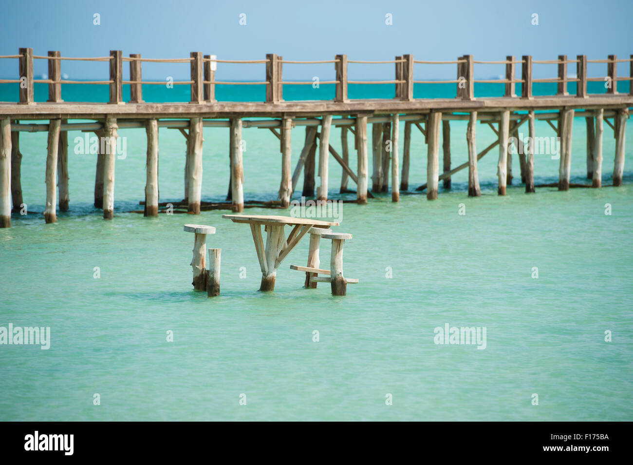 Long wooden jetty in the sea from a tropical island lagoon on beach ...