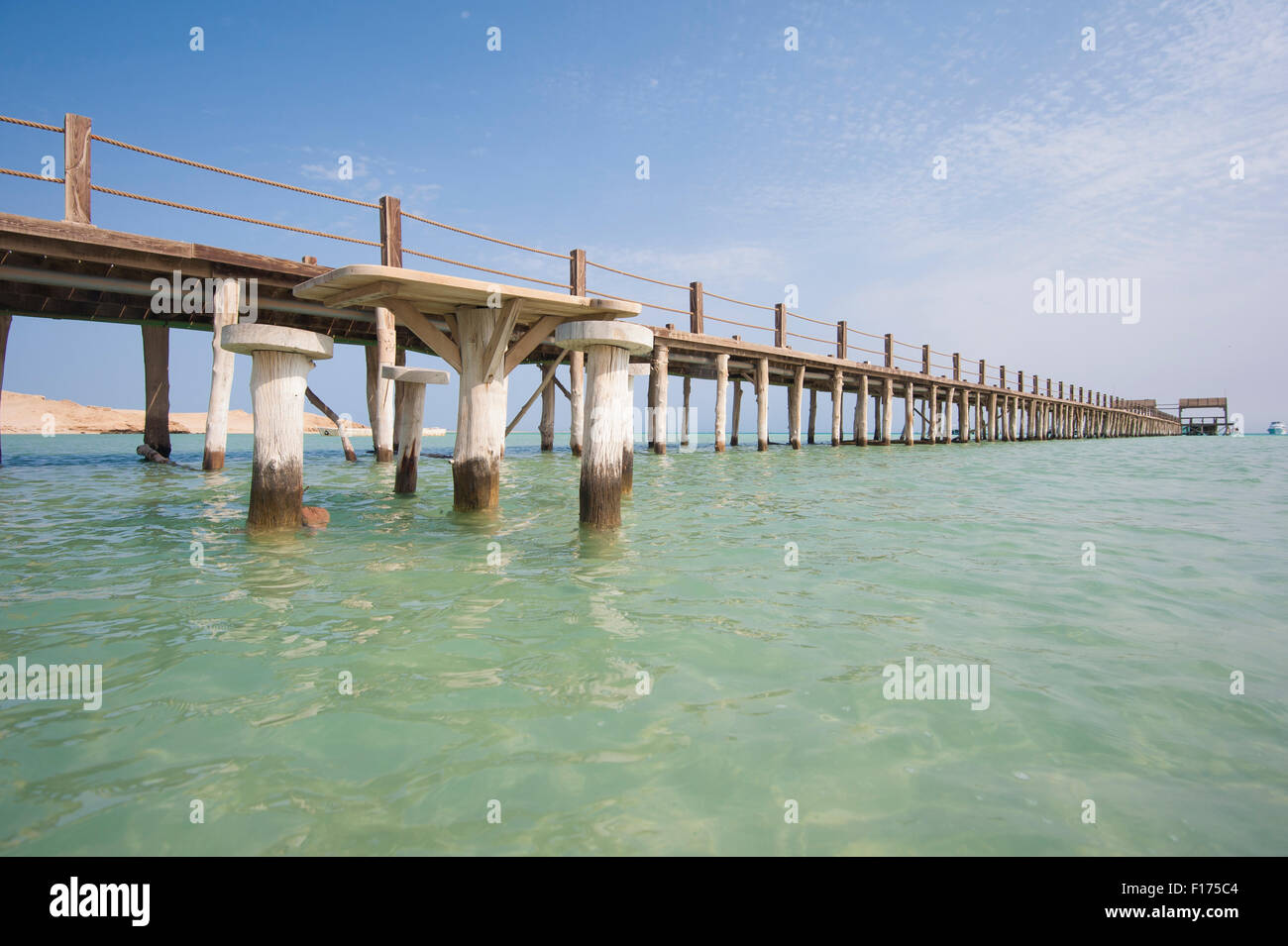 Long wooden jetty in the sea from a tropical island lagoon on beach ...