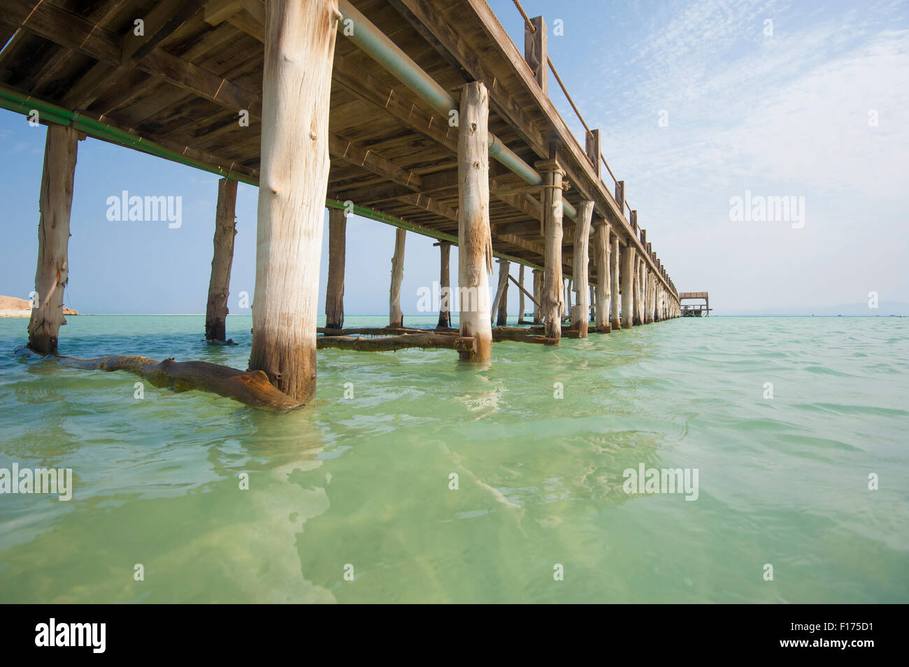 Long wooden jetty in the sea from a tropical island lagoon on beach ...