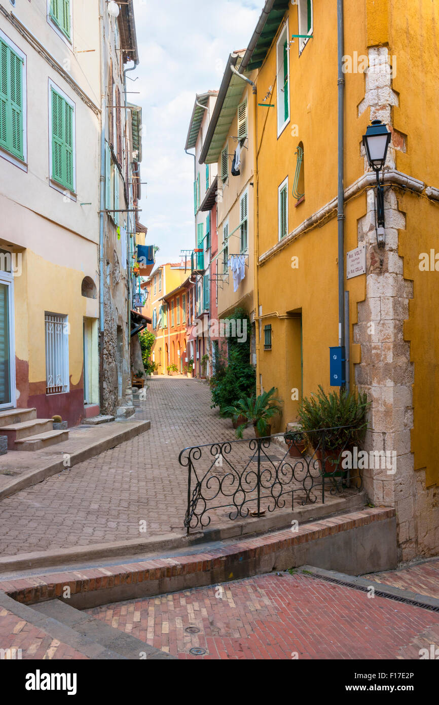 Narrow street intersection with colorful old buildings and green potted ...
