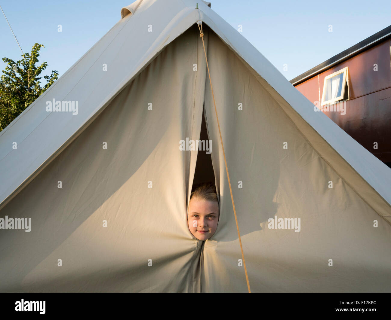 A ten year old girl pokes her head out from a tent Stock Photo - Alamy