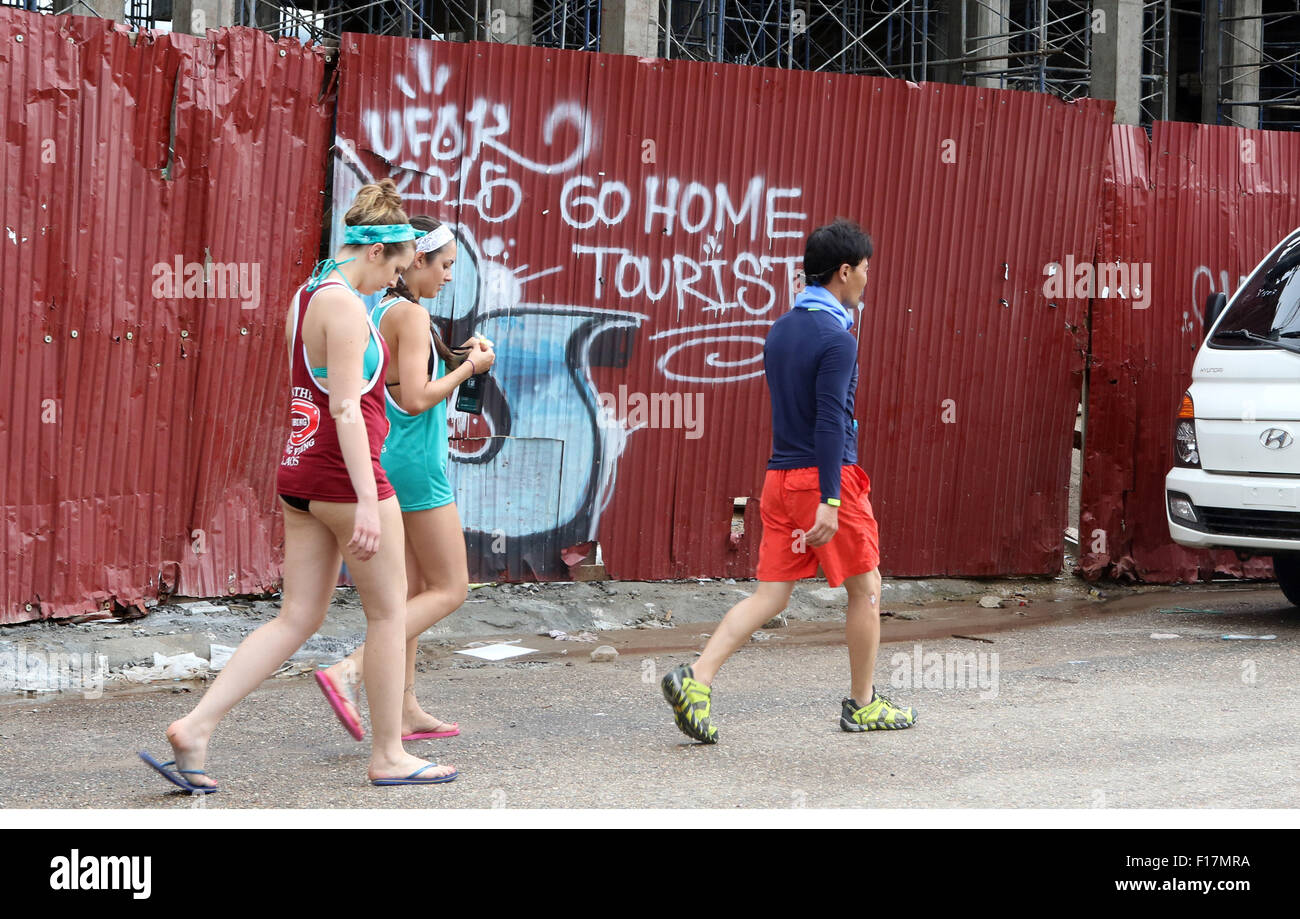Tourist Go Home graffiti on wall girls walk past Stock Photo - Alamy