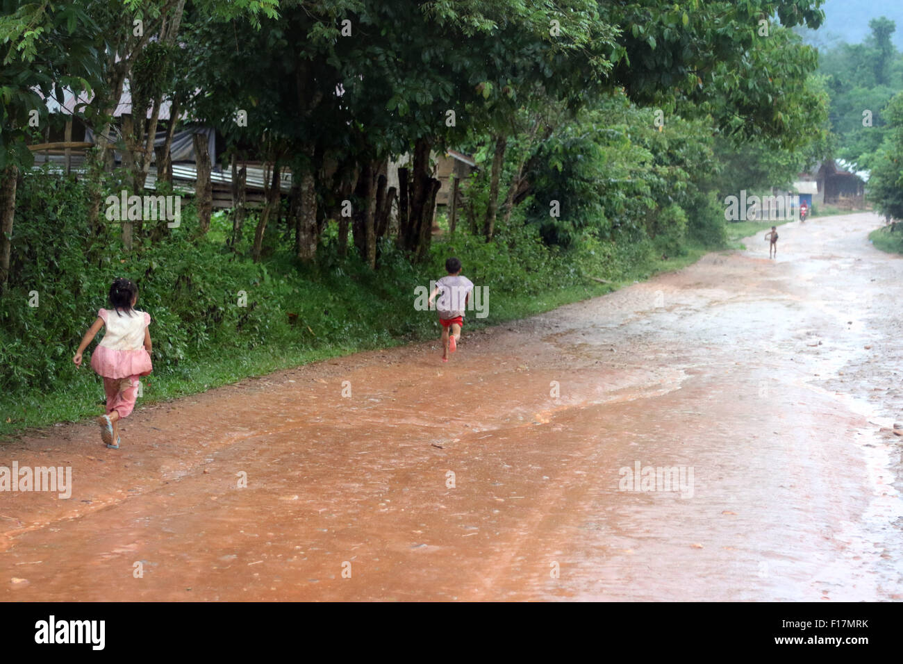 Kids running through rain on muddy road storm Stock Photo - Alamy
