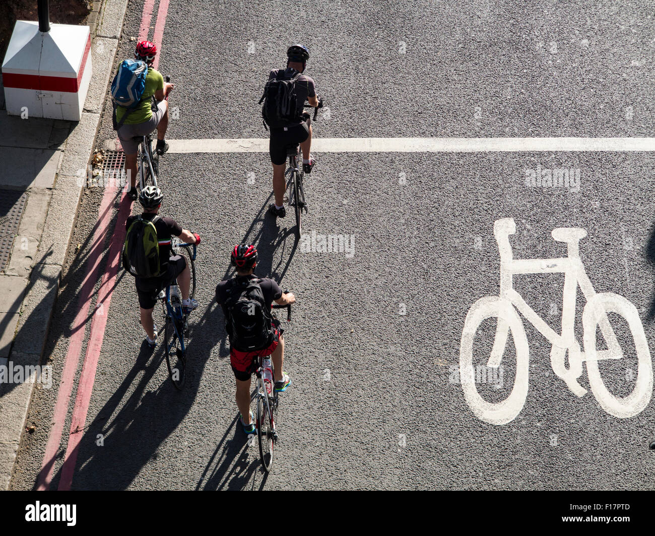 A cyclist at the traffic lights in afternoon sunlight on a busy high ...