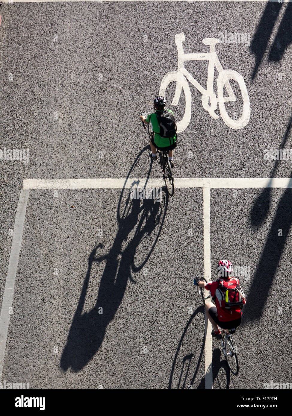 A cyclist at the traffic lights in afternoon sunlight on a busy high ...