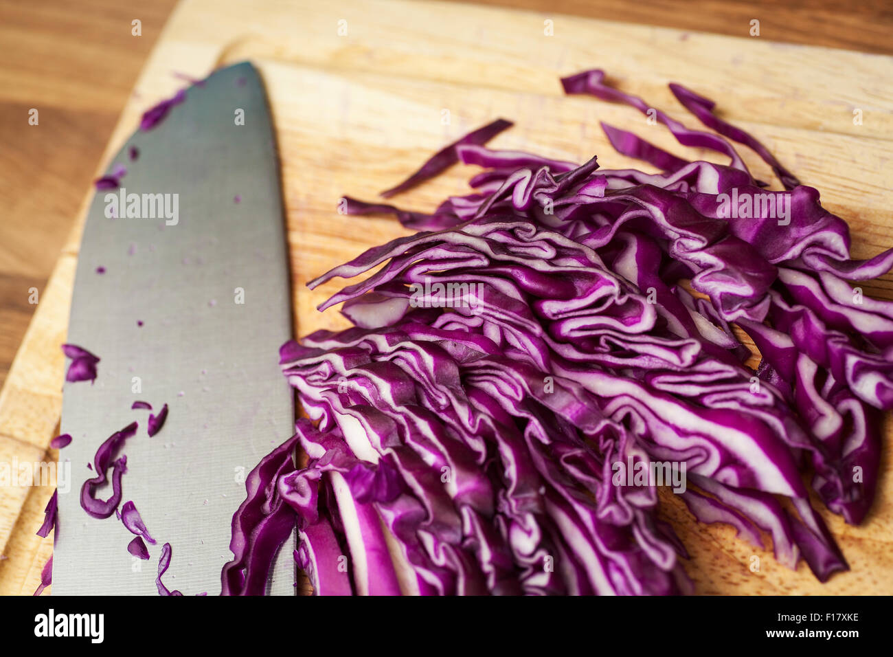 Sliced fresh red cabbage on a small wooden chopping board and cooks ...