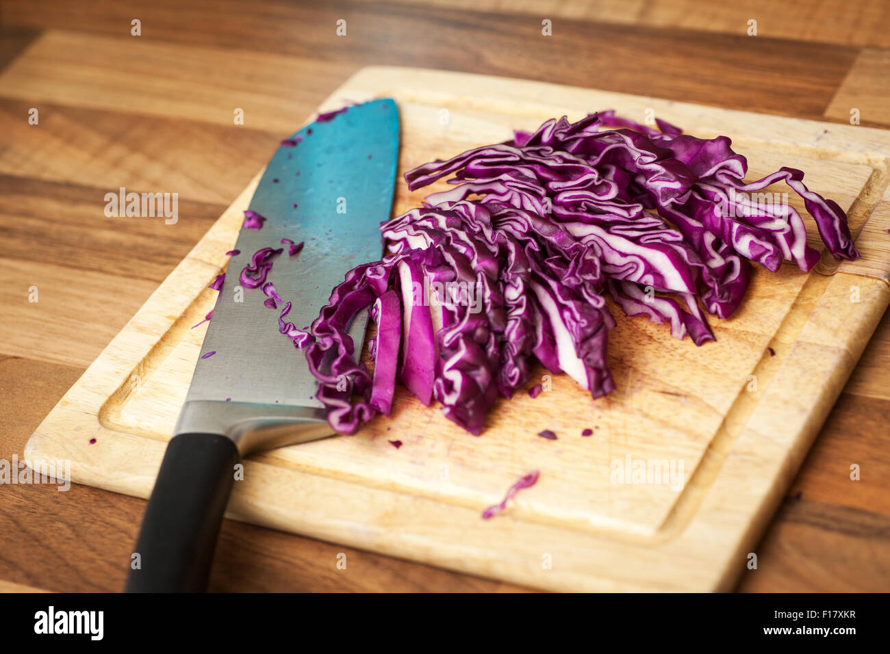 Sliced fresh red cabbage on a small wooden chopping board and cooks ...