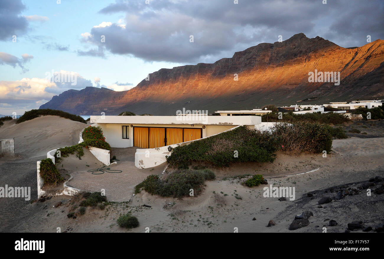 Bungalow in Playa de Famara beach dunes at sunset with Risco de Famara ...
