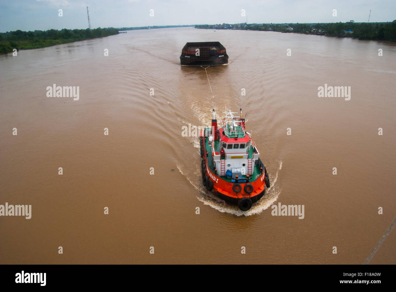 A tugboat is pulling an empty barge on Batanghari river in Muara Sabak ...