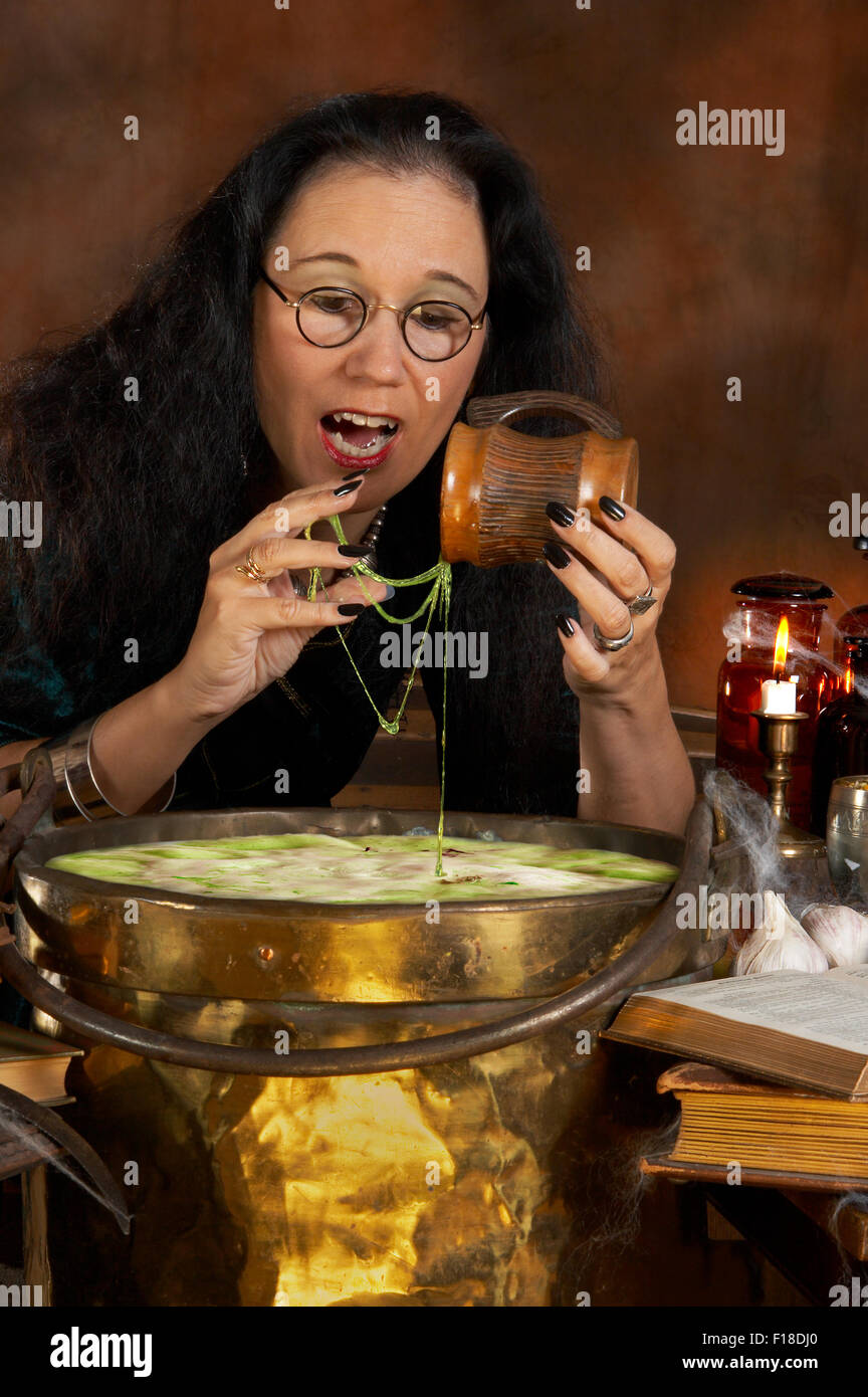 Halloween witch dripping green slime into her cauldron Stock Photo - Alamy