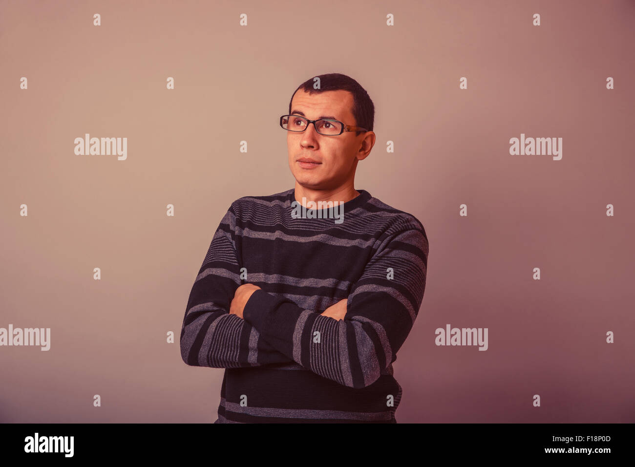 European-looking man of 30 years teacher thinks glasses on gray Stock ...