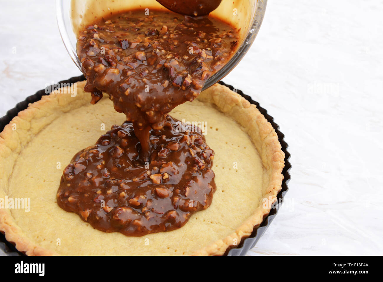 Pouring sticky, sweet pecan pie filling into a blind-baked shortcrust ...
