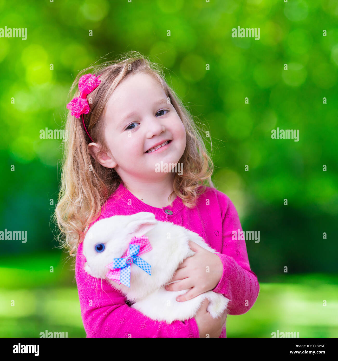 Children play with real rabbit. Laughing child at Easter egg hunt with ...