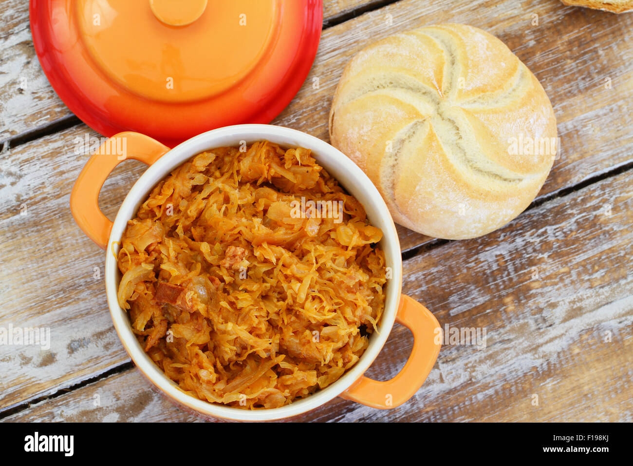 Polish bigos in saucepan and bread roll on rustic wooden surface Stock ...