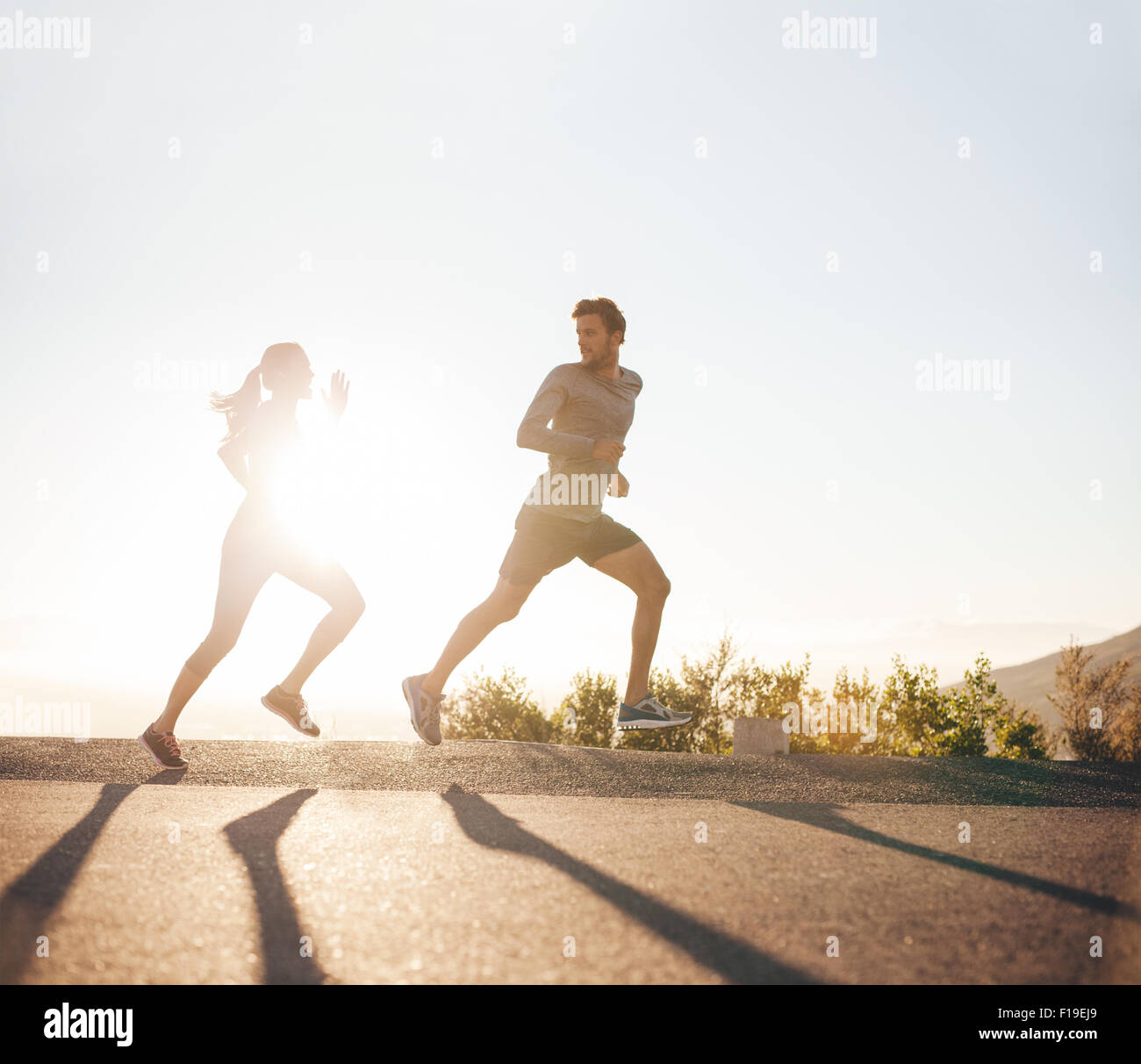 Young people running on country road with bright sunlight. Outdoor shot ...