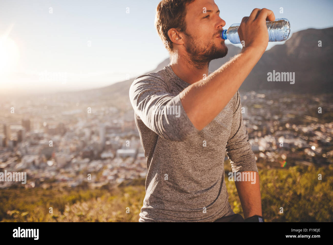 Young runner taking a break after morning run drinking water. Young man ...