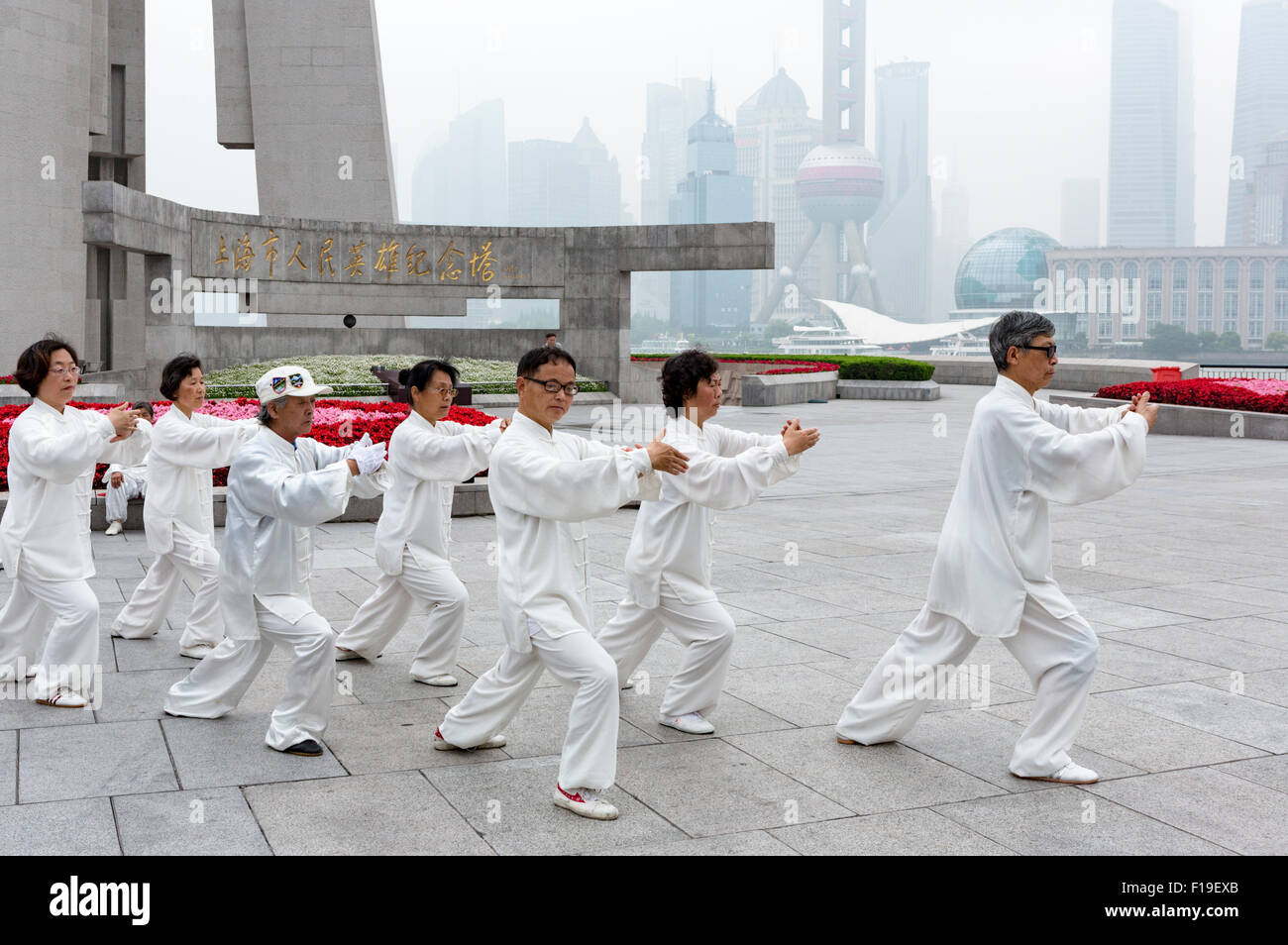 Tai Chi group in matching gear exercises near Shanghai's Bund in view ...