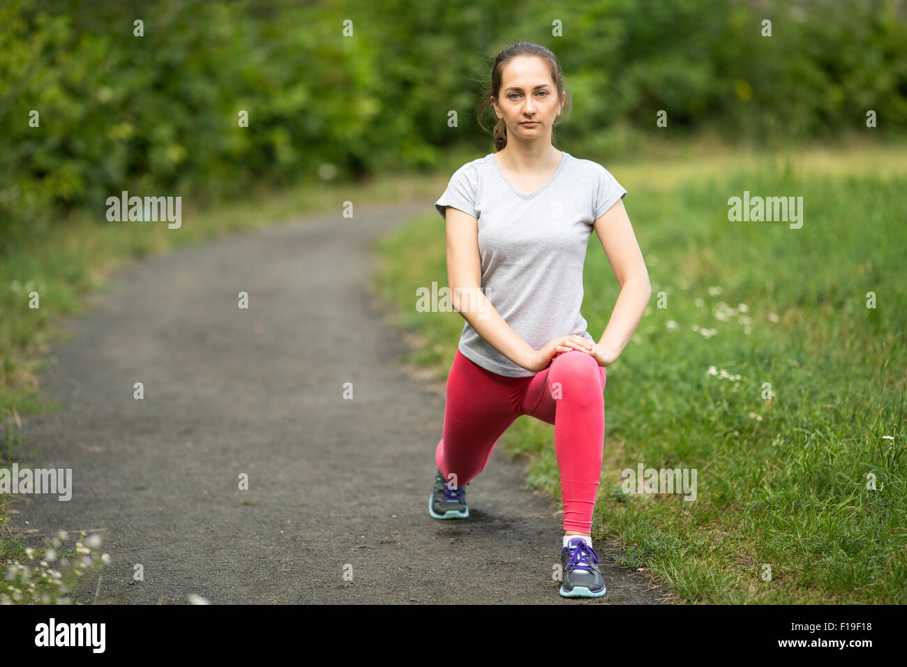 Young sporty woman doing exercise warm-up before running in park in ...