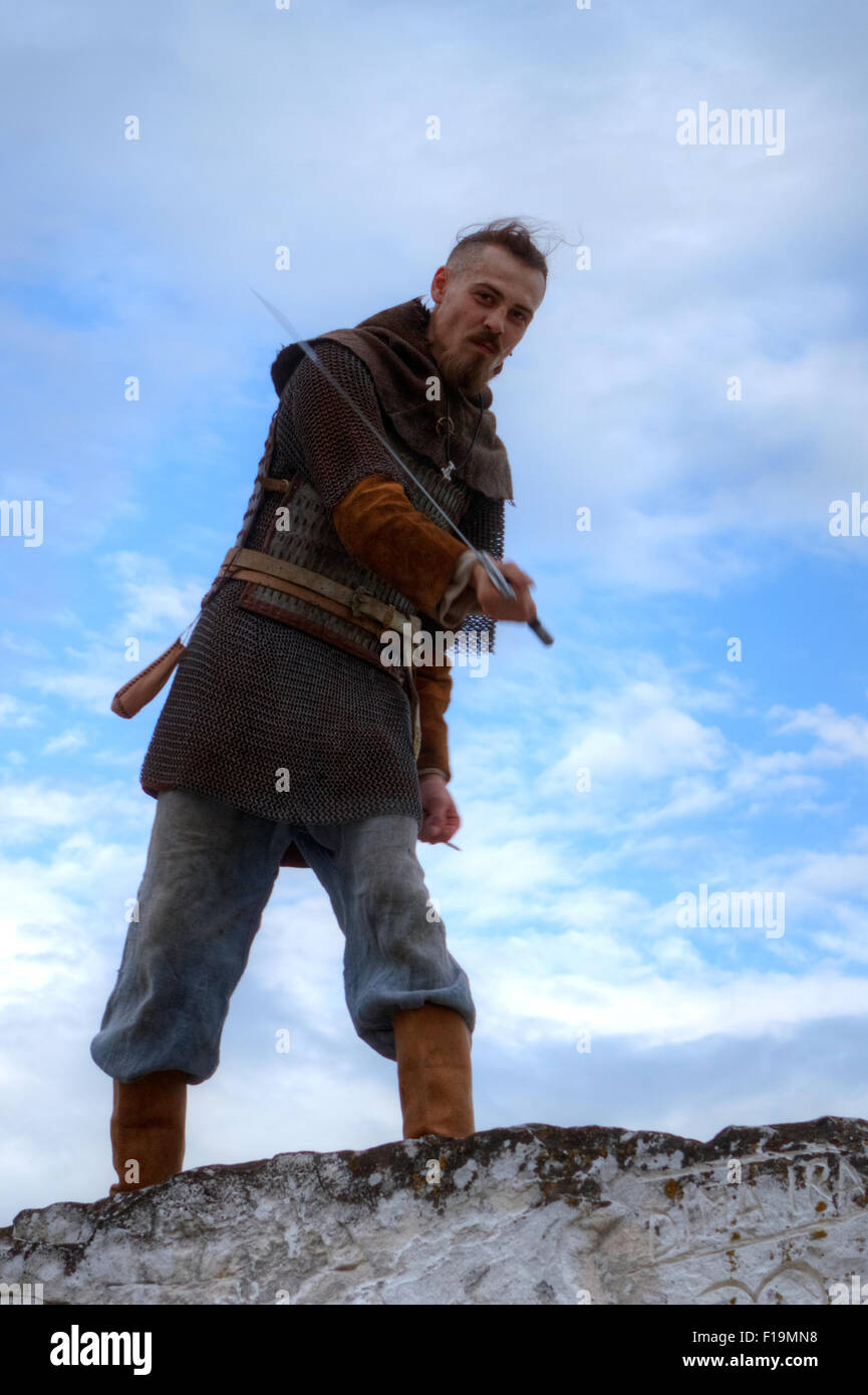 Knight on a rock with a sword against blue cloudy sky Stock Photo - Alamy