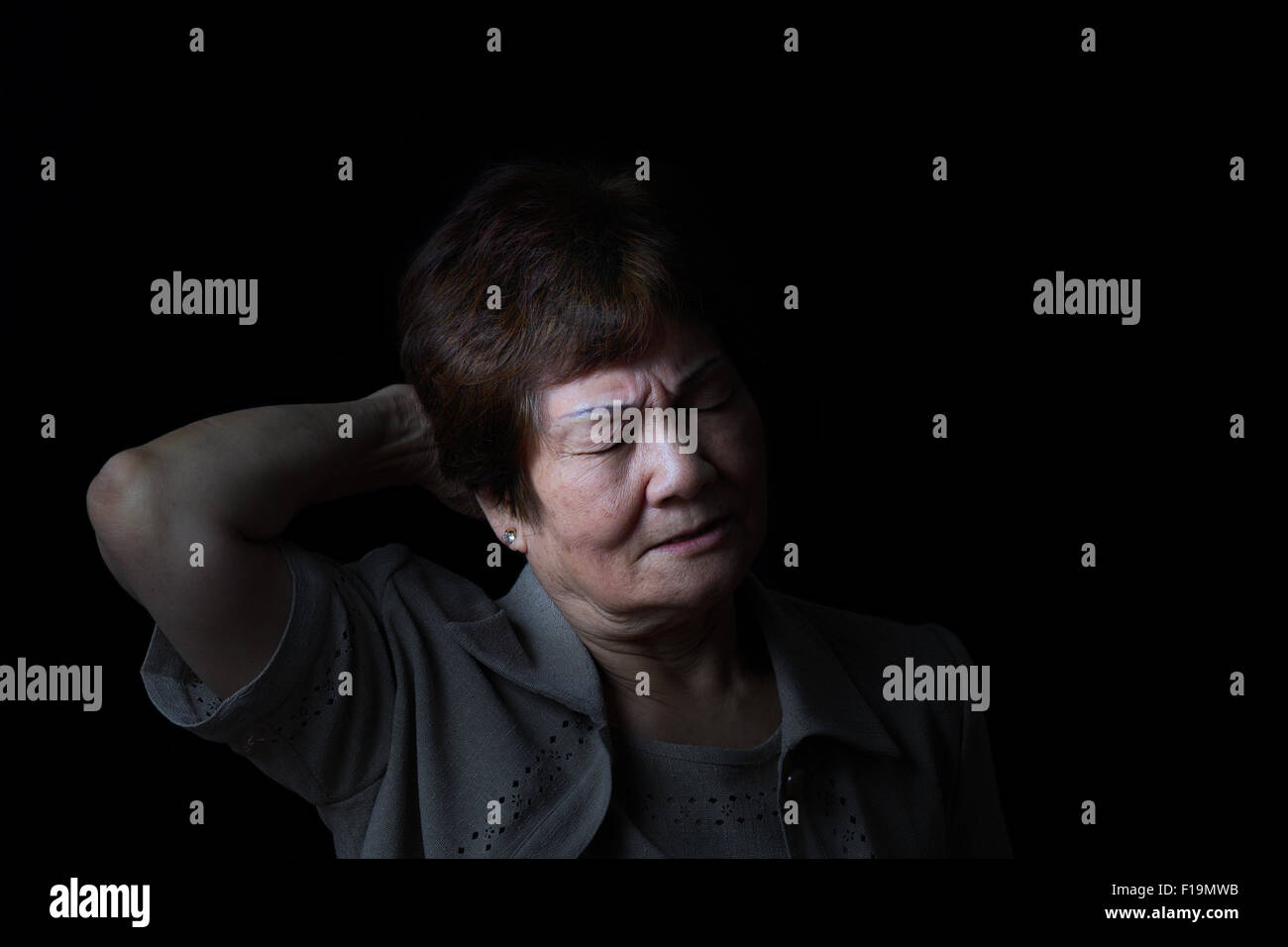 Senior woman touching the back of her head while displaying pain on ...