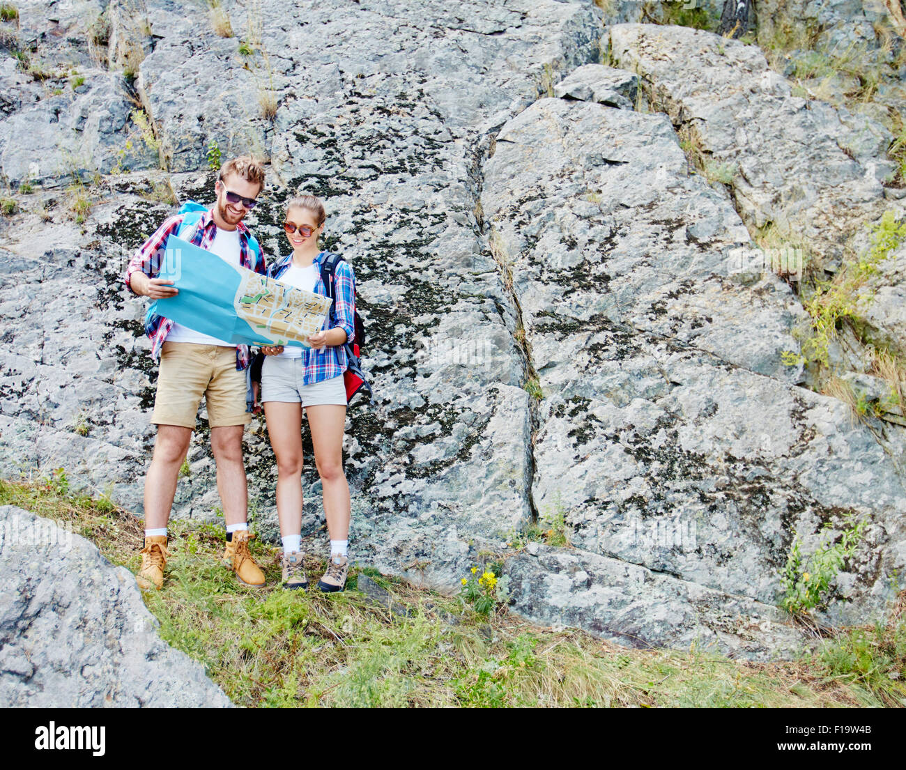 Happy hikers looking at map while standing by rock Stock Photo - Alamy