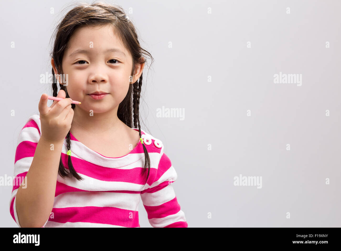 Happy little girl eating snack on white background Stock Photo - Alamy