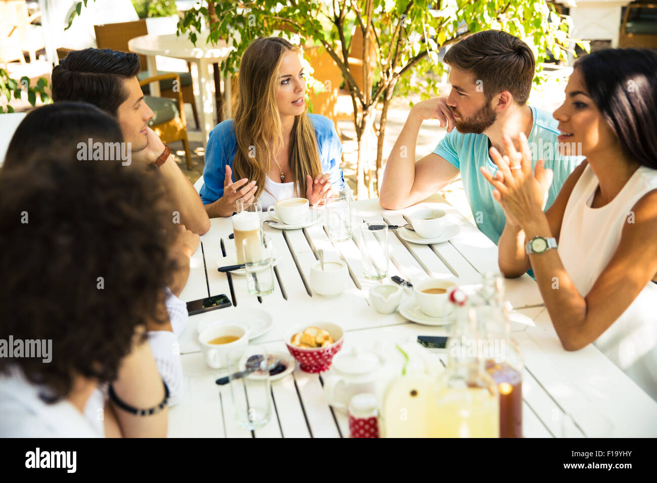 Smiling young friends enjoying meal in outdoor restaurant Stock Photo ...