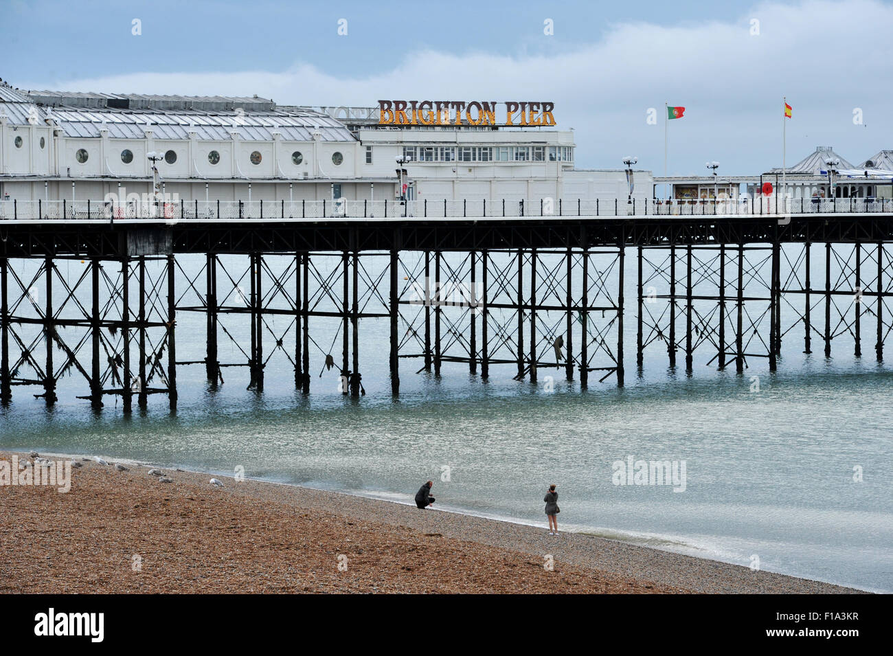 Brighton UK - A couple take a walk on Brighton beach by the pier in the ...