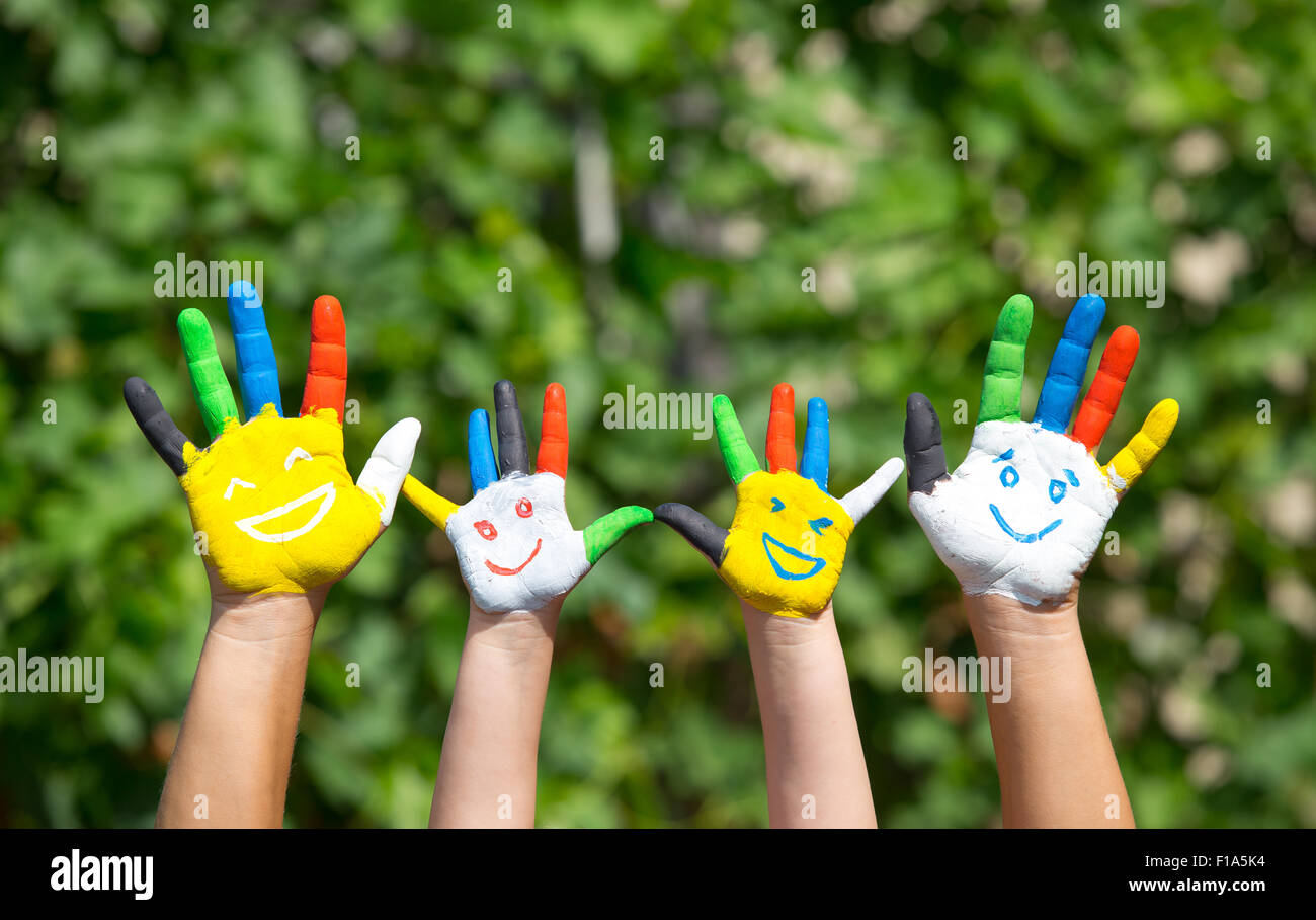 Colored hands with smile painted in colorful paints against green ...