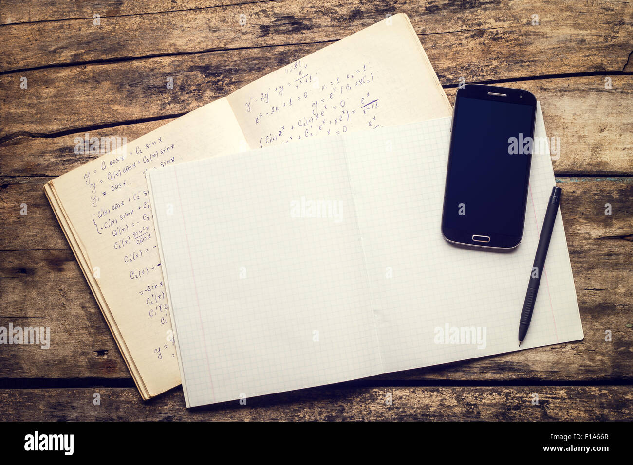 Warm color toned vintage image of exercise book with smartphone and pen ...