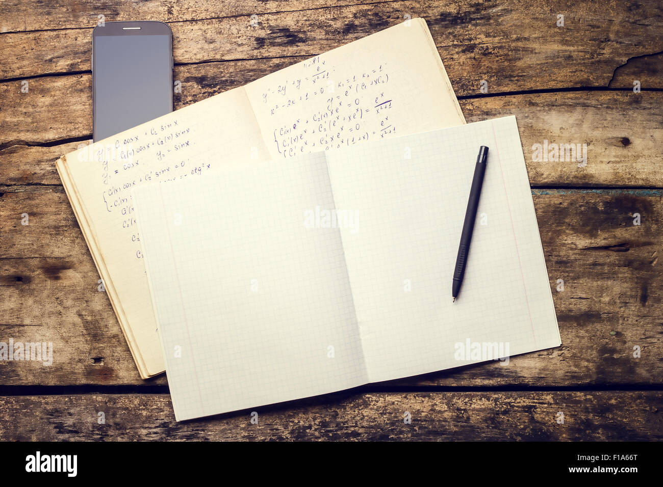Warm color toned vintage image of exercise book with smartphone and pen ...