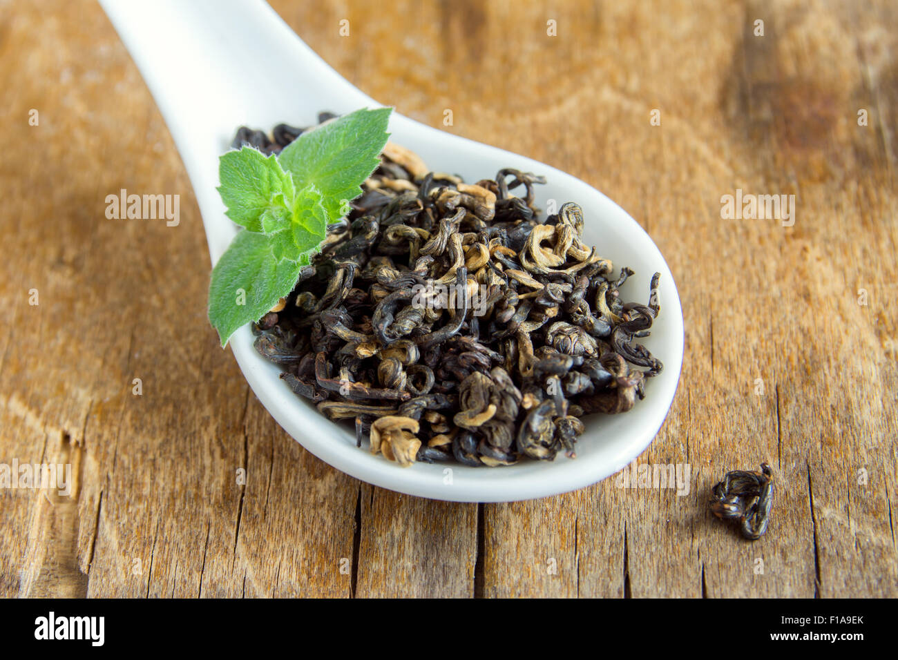 Elite dried chinese black tea with mint on spoon over rustic wooden ...