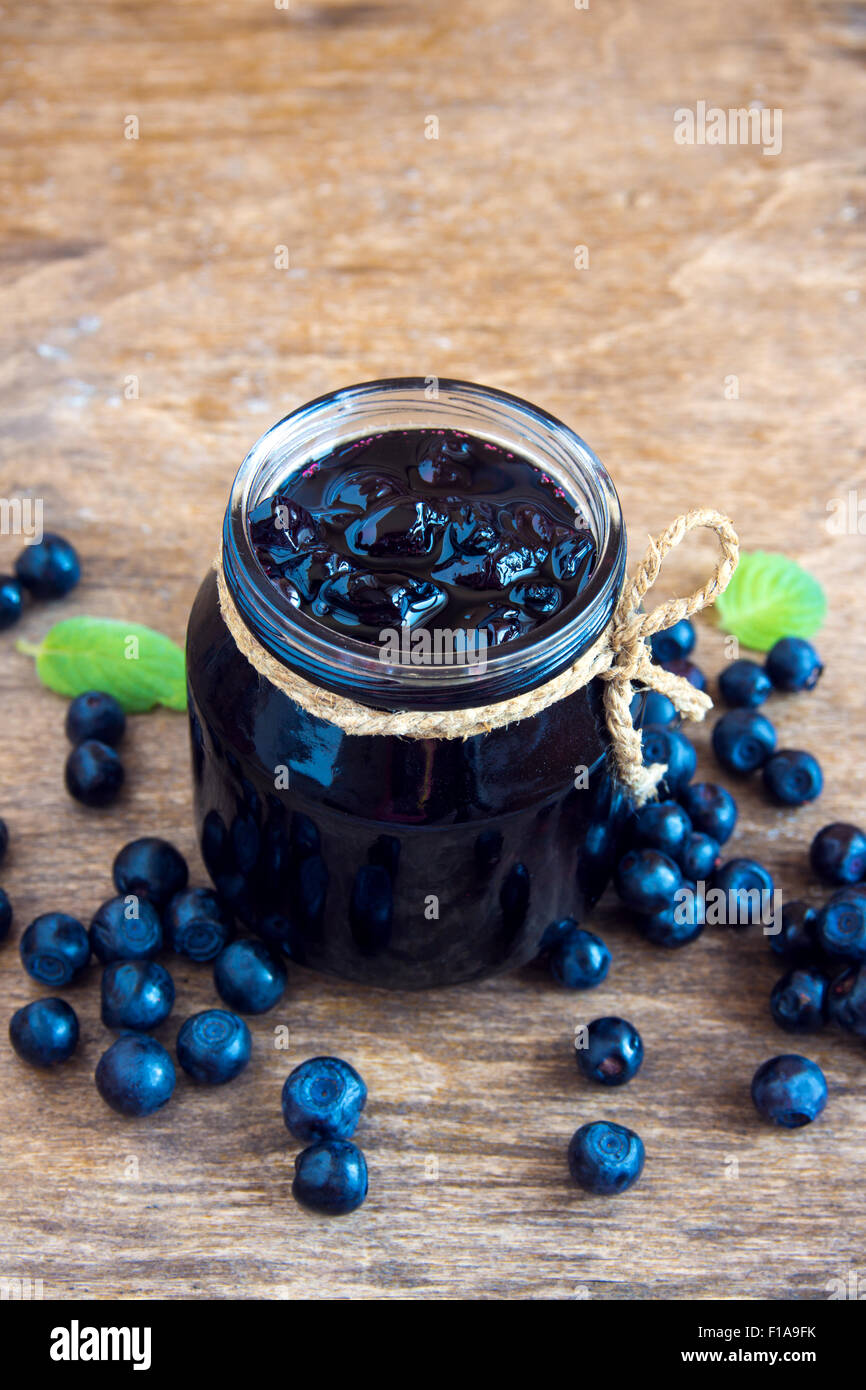 Blueberry jam in jar with berries and leaves over rustic wooden table ...