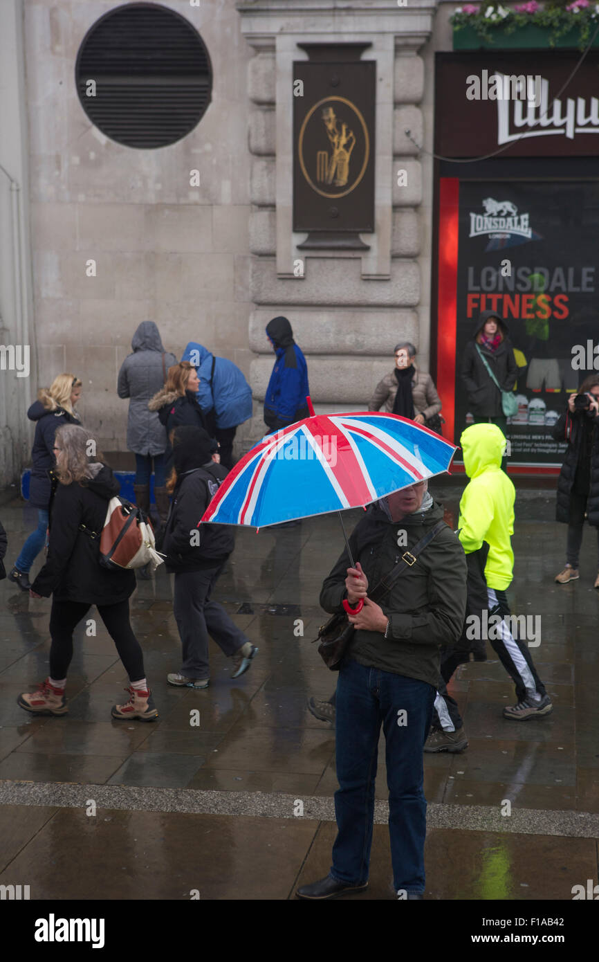 A man holding an umbrella showing the British flag (Union Jack) in a ...