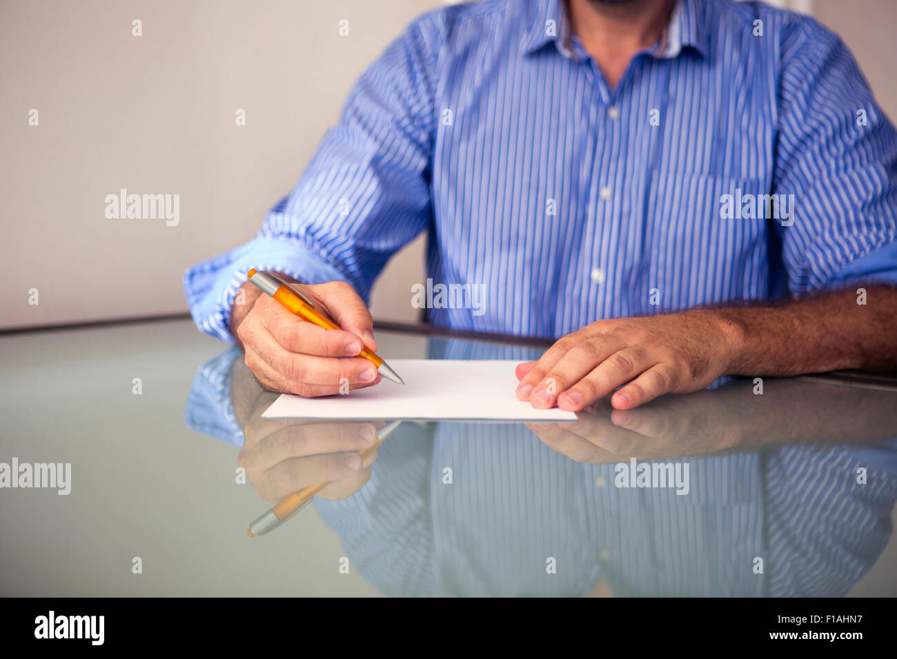 closeup of man sitting at table and writing on a piece of paper Stock ...