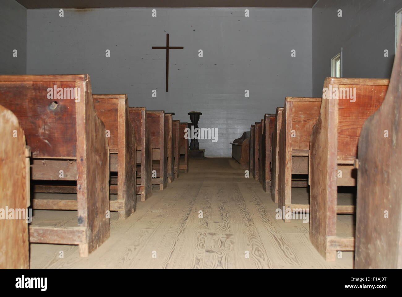 A view up the isle of an old church, with a cross in the background ...