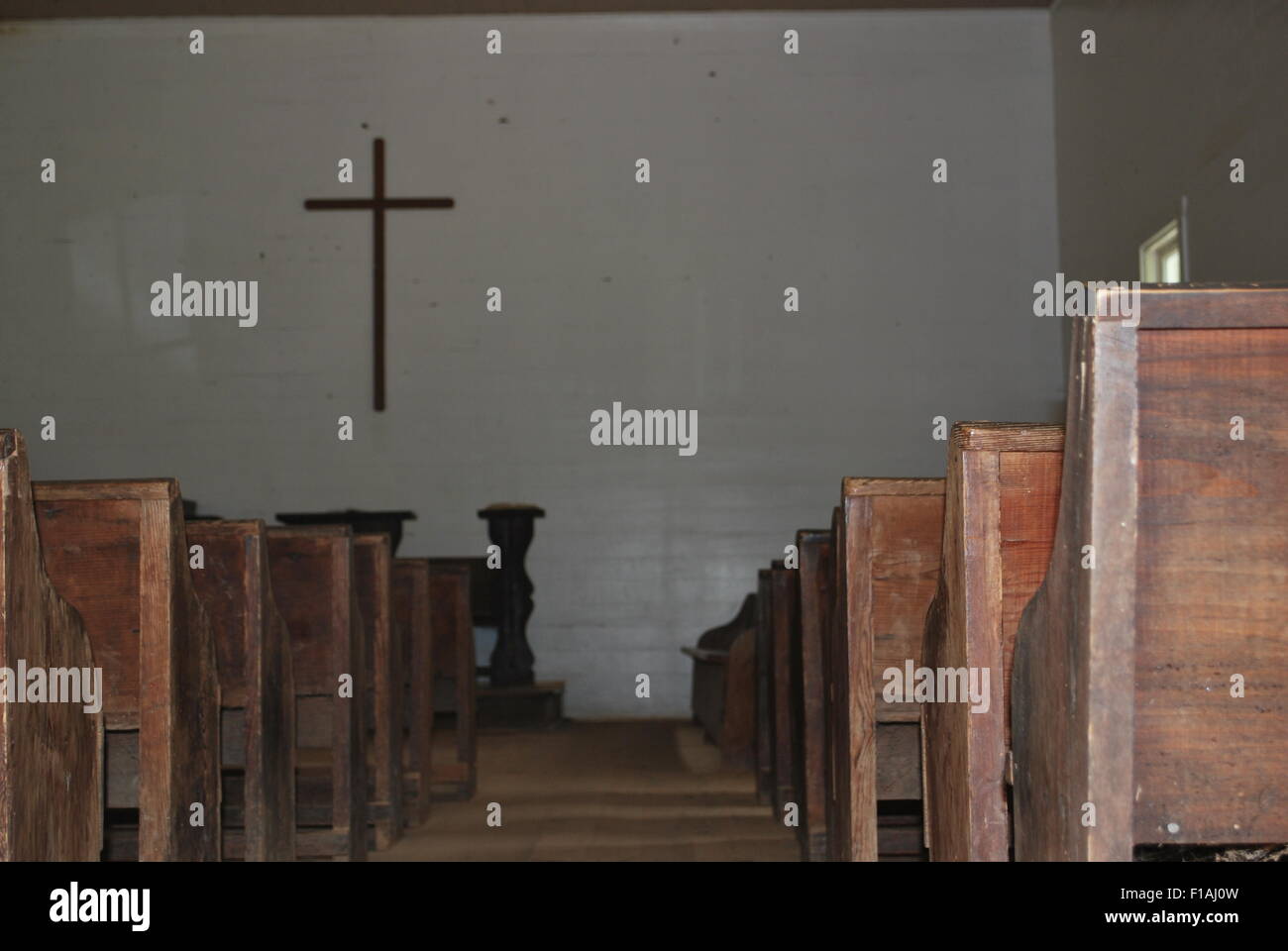 A view up the isle of an old church, with a cross in the background ...