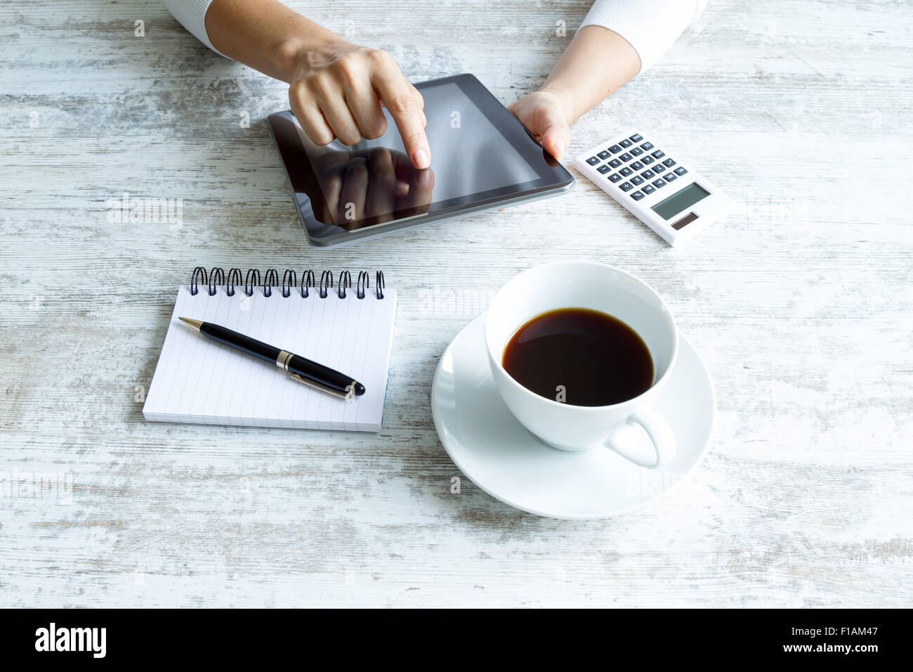 Using the tablet meanwhile drinking coffee Stock Photo - Alamy