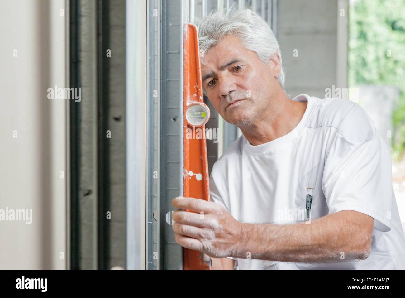 Mason using an orange spirit level Stock Photo - Alamy