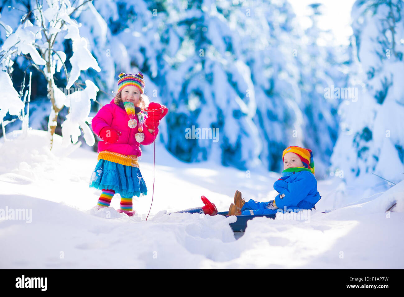 Little girl and baby boy enjoying a sleigh ride in the Alps mountains ...