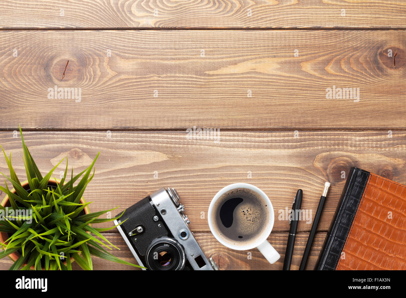Camera and supplies on office wooden desk table. Top view with copy ...