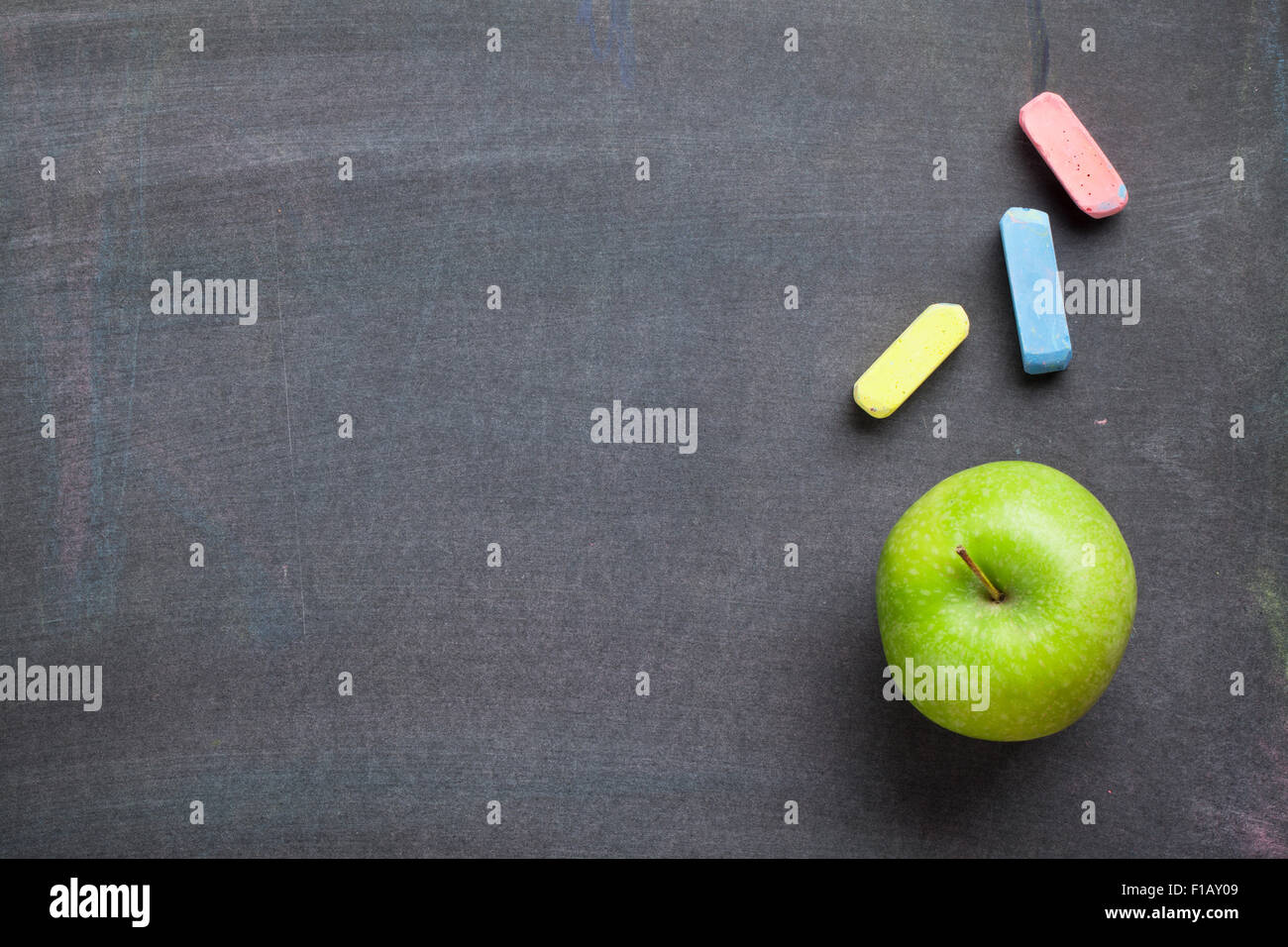 Colorful chalk and apple on blackboard background. Top view with copy ...