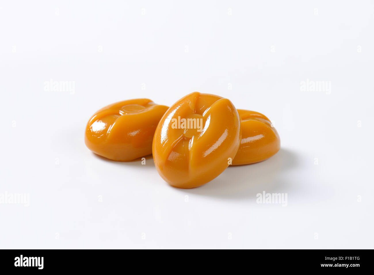 three caramel candies on white background Stock Photo - Alamy