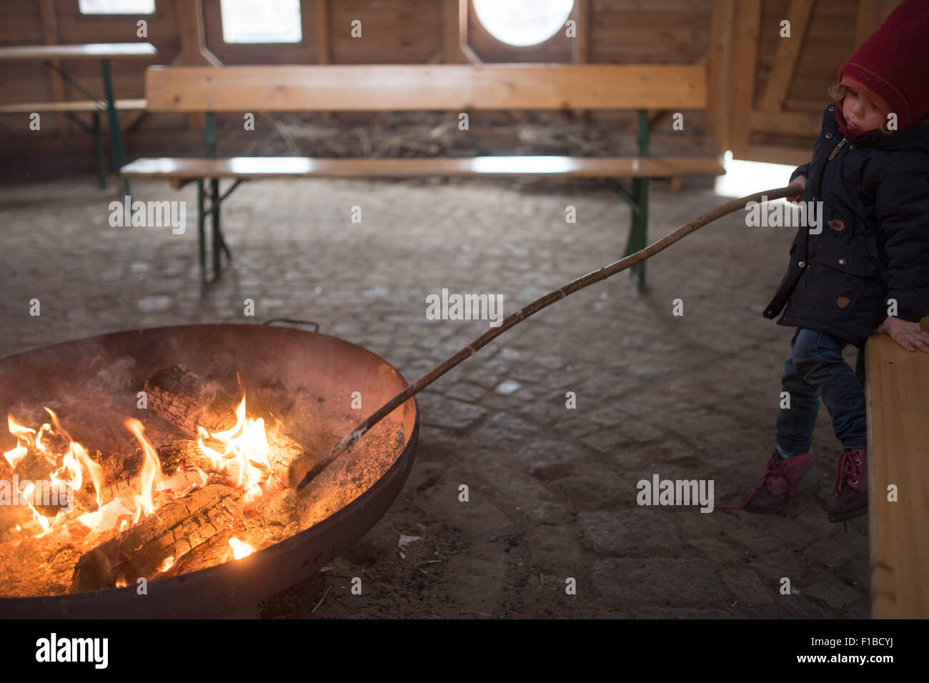 Little girl pokes in a wood fire herhum Stock Photo - Alamy