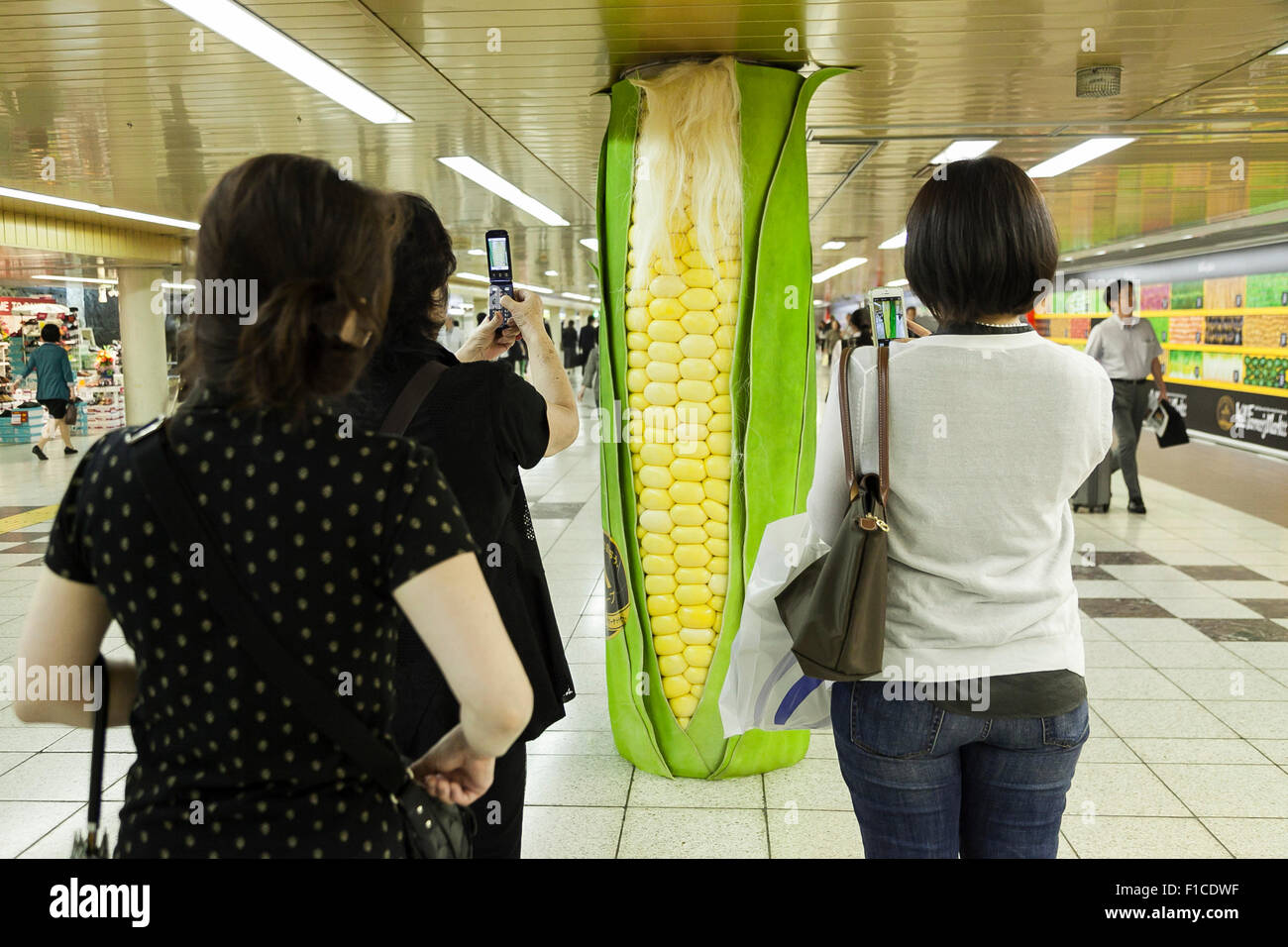 People take a picture of a column displaying a giant corn in the Tokyo ...