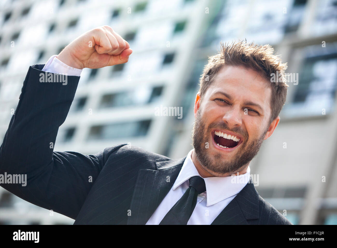 A young successful man, male executive businessman arms raised ...