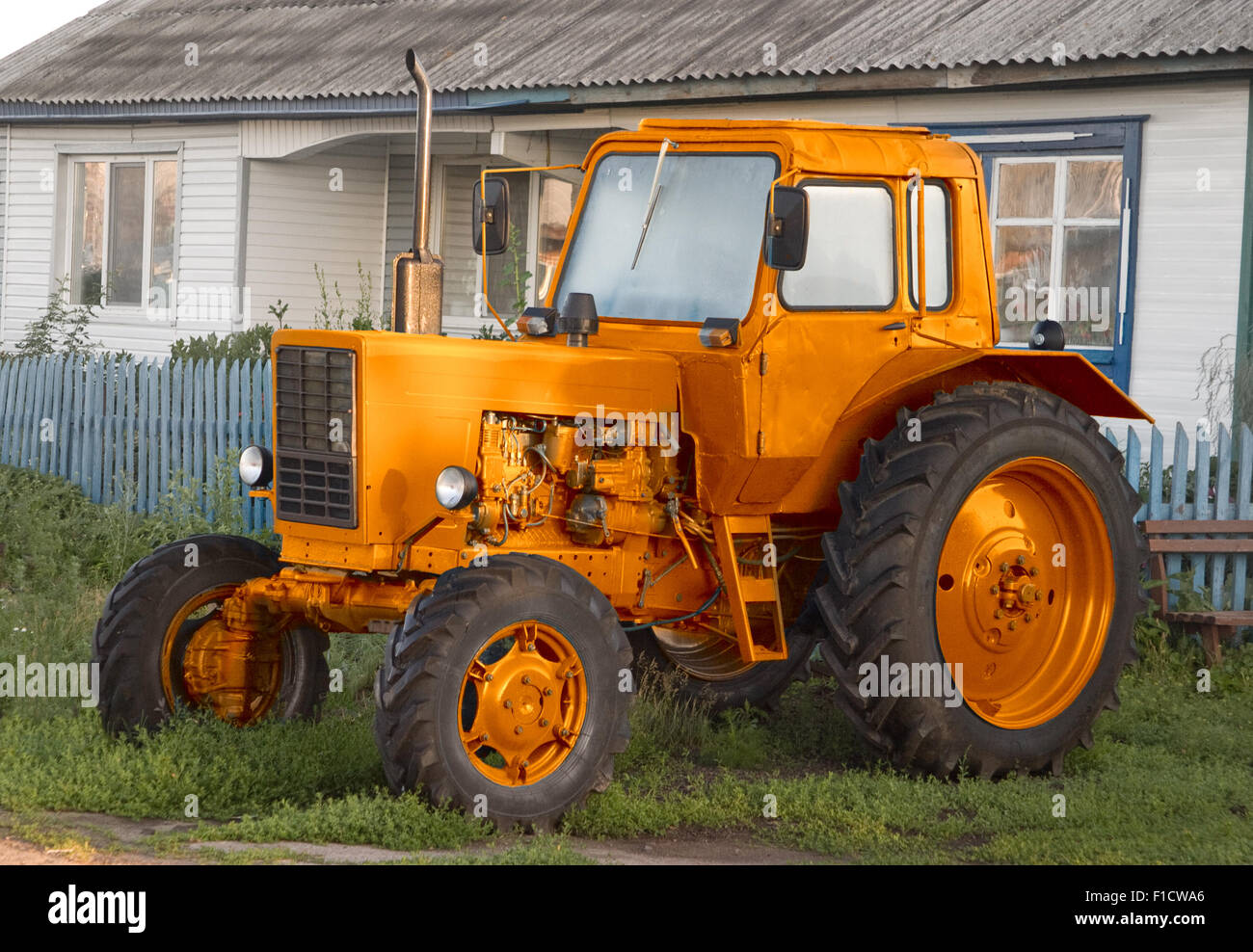 Farm tractor near the village house Stock Photo - Alamy